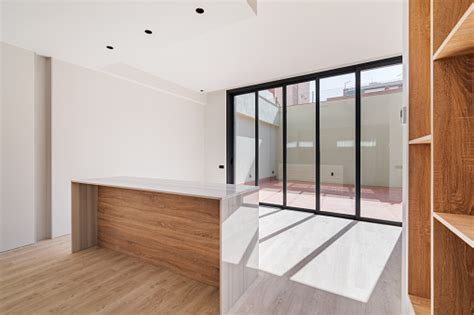 커다란 창문을 통해 들어오는 자연 채광이 들어오는 새로 단장한 아파트의 빈 내부 섬과 나무 가구가 있는 현대적인 주방 0명에 대한 스톡 사진 및 기타 이미지 Istock