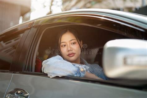 A Positive Asian Woman Sits In Her Car Looking Out The Window And