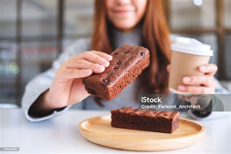 커피를 마시는 동안 브라우니 케이크 한 조각을 들고 먹는 아름다운 여자 건강에 좋지 않은 음식에 대한 스톡 사진 및 기타 이미지 건강에 좋지 않은 음식 달콤한 음식