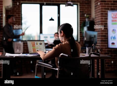 Female Manager Living With Disability Analyzing Website On Laptop Working With Statistics In