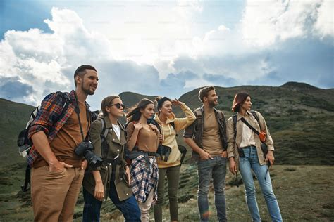 모험을 떠날 준비가 되었습니다 활발하고 열정적인 젊은이들이 큰 배낭을 메고 서서 산에 있는 동안 먼 곳을 주의 깊게 바라보고