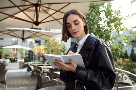 매력적인 젊은 사업가 카피라이터 저널리스트 하얀 메모장에 글을 쓰고 도시 공공 배경에 야외에 앉아 있는 친밀한 초상화 거리가 먼에 대한 스톡 사진 및 기타 이미지 Istock