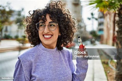 거리에서 전자 담배를 들고 자신감있게 웃고있는 젊은 중동 여성 담배에 대한 스톡 사진 및 기타 이미지 담배 보기 정적 활동 사람들 Istock