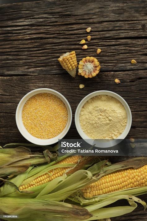 폴렌타 옥수수 그릿과 옥수수 가루를 나무 테이블에 있는 도자기 그릇에 담습니다 그릇 옆에 옥수수와 옥수수 조각의 귀 글루텐 프리 건강한 식습관 0명에 대한 스톡 사진 및