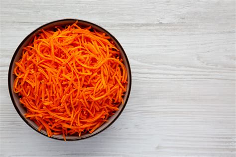 생 오렌지 당근 갈가리 찢어 그릇에 흰색 나무 배경 평면도 머리 위에서 위에서 평평하게 놓여 있습니다 공간을 복사합니다 0명에