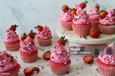 종이 케이크 케이스에 수제 핑크 벨벳 딸기 컵 케이크의 배치의 이미지 핑크 버터 착빙 파이프 소용돌이에 딸기 설탕 공예 심장 모양과 구 뿌리 대리석 케이크 스탠드에 전경에