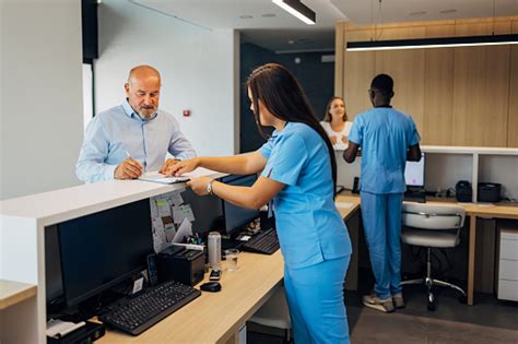 리셉션 데스크에서 노인이 의료 양식을 작성하는 데 도움을 주는 아시아 의료 종사자 25 29세에 대한 스톡 사진 및 기타 이미지 25 29세 30 34세 35 39세