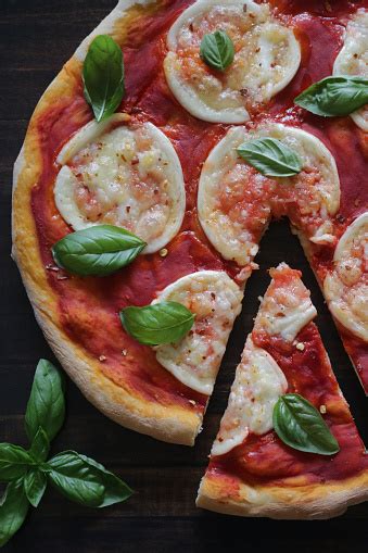 얇게 썬 갓 구운 수제 마르게리타 피자 골든 버팔로 모짜렐라 치즈 서클 풍부한 토마토 마리나라 소스 신선한 바질 잎 토핑 나무 도마 배경 높은 전망 0명에 대한 스톡 사진
