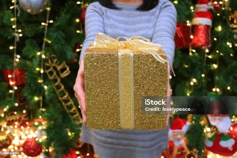 여성 골드 반짝이 광장 나눠 누군가에게 배경에서 흐리게 크리스마스 트리 골드 리본 활과 포장 선물 상자 모양 감사에 대한 스톡