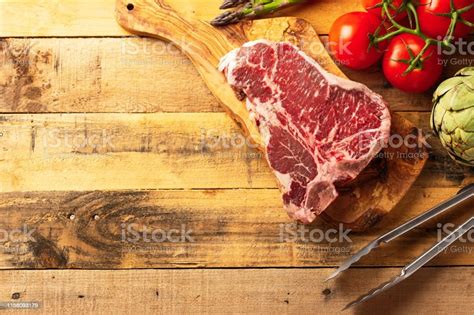 나무 배경에 신선한 야채와 집게와 대리석 쇠고기 스테이크의 신선한 원시 조각 도마에 레스토랑 메뉴 홈 메뉴 맛있는 음식 미식 요리 배경 고기에 대한 스톡 사진 및 기타