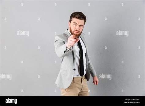 Portrait Of An Angry Businessman Dressed In Suit Standing And Pointing Finger At Camera Isolated