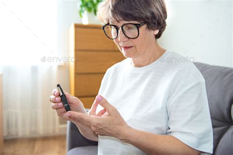 Diabetic Mature Woman Checking Blood Glucose Levels With Glucose Meter At Home Diabetes And