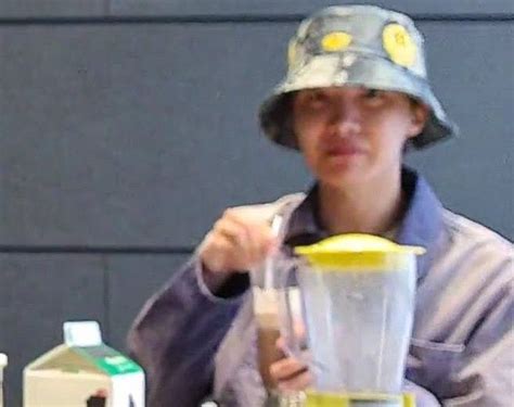 A Woman Wearing A Hat And Holding A Blender In Her Hand While Sitting