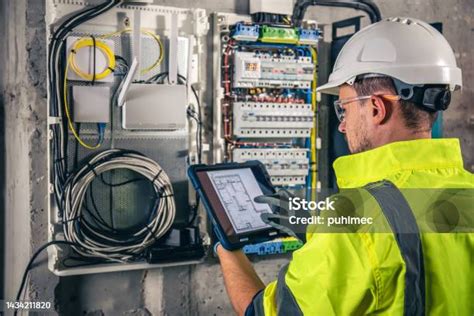 퓨즈가있는 배전반에서 일하는 전기 기술자 인 Man은 태블릿을 사용합니다 분전반에 대한 스톡 사진 및 기타 이미지 분전반
