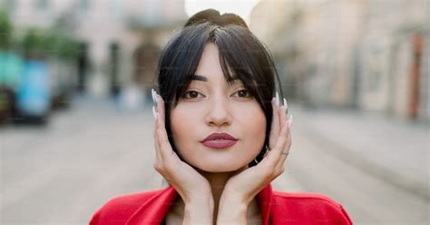 검은 머리와 패션 메이크업을 한 예쁜 갈색 머리 아시아 여성 모델의 클로즈업 얼굴 야외 초상화 손바닥에 얼굴을 기대고 오래된