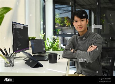 Young Male Website Developer Sitting Front Of Computers With Coded Data