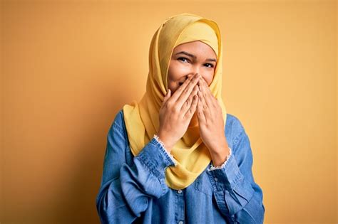 젊은 아름다운 여자 곱슬 머리 를 입고 아랍 전통 히잡 위에 노란색 배경 웃음과 부끄러운 웃음 으로 입을 덮고 가십과 스캔들 개념 Scandal에 대한 스톡 사진 및 기타