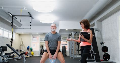 체육관에서 케틀벨로 운동하는 스포츠 의류를 입은 노인에게 적합합니다 개인 트레이너가 클립보드에 진행 상황을 기록하고 있습니다 사진 Unsplash의 슬로바키아 이미지