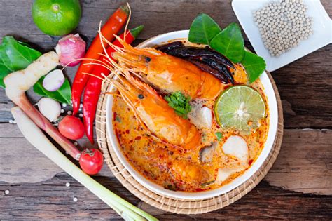 톰 얌 궁 또는 새우 수프 매운 새 수프 태국의 전통 음식은 상단 보기에서 오래 된 나무 배경에 흰 접시에 밥과 함께 칠리 라임 레몬그라스 라임 잎을 포함 합니다 건강한