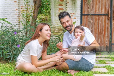 정원에서 뭔가를 손가락을 가리키는 동안 함께 어머니와 함께 그녀의 아버지 특종에 앉아 쾌활한 귀여운 어린 소녀 딸과 함께 부모는 집에서 휴식을 취합니다 라이프 스타일 휴식