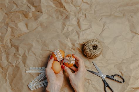 레이스와 밧줄로 크래프트 종이에 부활절 달걀을 장식합니다 구겨진 크래프트 종이 배경에 세 부활절 달걀 여자는 손에 계란을 들고 4월에 대한 스톡 사진 및 기타 이미지