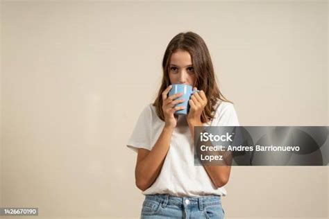 베이지 색 스튜디오 배경에 고립 된 핫 초콜릿 한 잔을 마시는 갈색 머리 머리를 가진 화려한 히스패닉 십대 소녀 아이에 대한 스톡 사진 및 기타 이미지 Istock