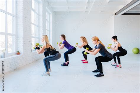 Side View Group Of Six Athletic Women Doing Squatting Exercises With