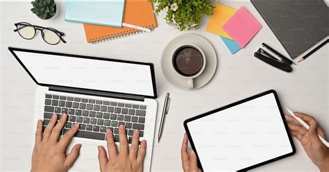 위의 모습은 흰색 사무실 책상에서 노트북 컴퓨터와 디지털 태블릿을 사용하는 두 젊은이입니다 사진 Unsplash의 사무실 이미지