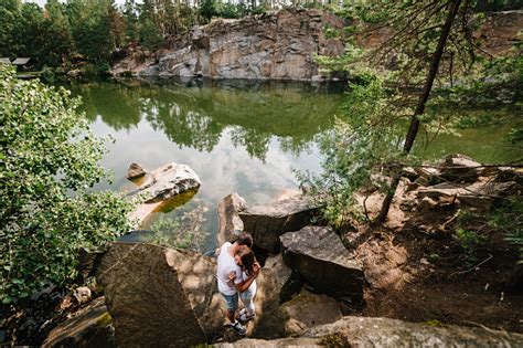 젊은 부부는 호수 근처에 돌을 포옹 한 남자와 여자는 바위의 배경에 서 있었다 평면도 자연 가 전체 길이 서로를 바라보 고 있습니다 2명에 대한 스톡 사진 및 기타 이미지