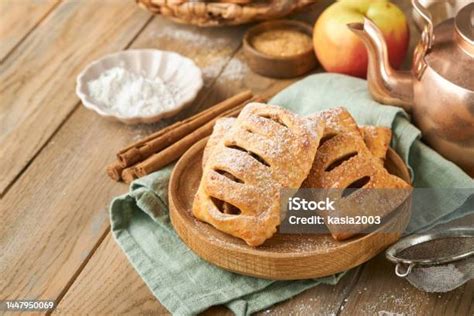 핸드 파이 미니 퍼프 페이스 트리 또는 사과로 채워진 핸드 파이와 나무 접시에 설탕 가루를 뿌린다 아침 식사를위한 빵 껍질과 수제 파이 스낵 소박한 사진 공간을 복사합니다