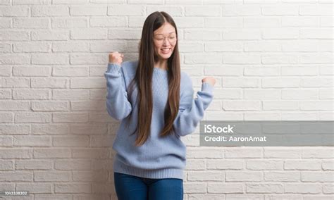 젊은 Chinise 여자 백색 벽돌 벽 매우 행복 하 고 무기와 우승자 제스처를 하 고 흥분을 통해 웃 고 성공을 위한 비명 축