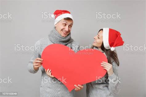 메리 재미 빨간색 산타 크리스마스 모자 회색 스웨터 스카프 회색 벽 배경 스튜디오 초상화에 고립 된 커플 여자 사람 행복 한 새