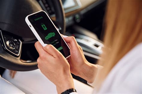 스마트 폰으로 내부에 앉아 있습니다 흰 옷을 입은 젊은 여자는 낮에 전기 자동차와 함께 있다 35 39세에 대한 스톡 사진 및 기타 이미지 Istock