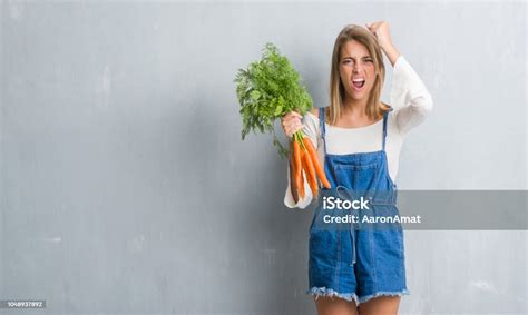 그런 지 회색에 아름 다운 젊은 여 자가 벽 신선한 당근 짜증과 분노 미친 제기 손으로 소리와 좌절 외치고 분노 개념 감정에 대한 스톡 사진 및 기타 이미지 Istock
