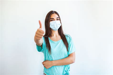 일회용 얼굴 마스크를 가진 아름다운 백인 젊은 여성 바이러스 및 감염 에 비해 보호 스튜디오 초상화 흰색 배경 개념 엄지 손가락을 보여주는 여자 20 24세에 대한 스톡