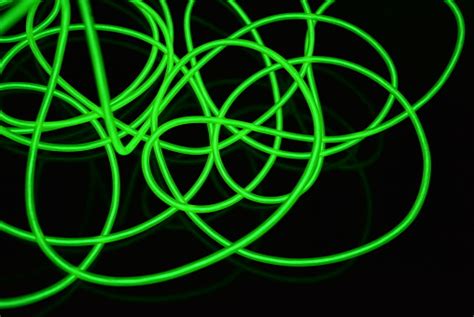 다른 모양과 구조를 가진 독성 녹색 발광 전기 발광 전선 검은 광택 표면에있는 석회 전기 발광 섬유 엘 와이어 및 특이한 원의