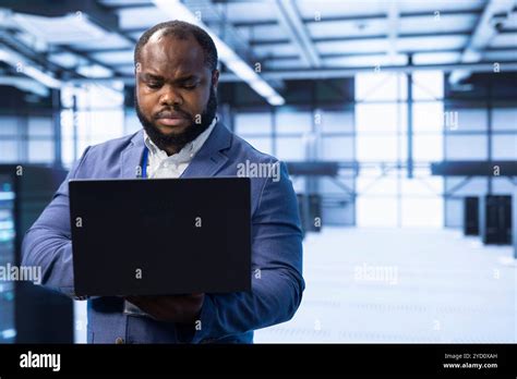Engineer In Server Room Using Laptop To Implement And Maintain Security Measures Protecting