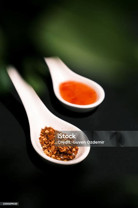 타이 칠리 플레이크와 달콤한 칠리 소스를 곁들인 흰색 세라믹 숟가락의 클로즈업 짙은 녹색 배경에 설정 정통 태국 향신료와 조미료 개념 0명에 대한 스톡 사진 및 기타 이미지