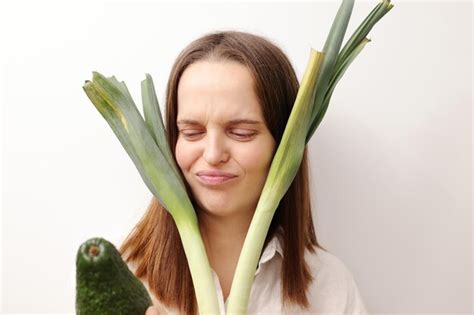 premium photo confused caucasian woman holding green leek and avocado supporting wellbeing