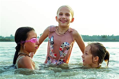 젖은 옷을 입고 강에서 노는 행복한 아이들 젊은 친구들은 강물에서 수영합니다 세 웃는 여자는 일몰에 물에서 재미를 가족에 대한