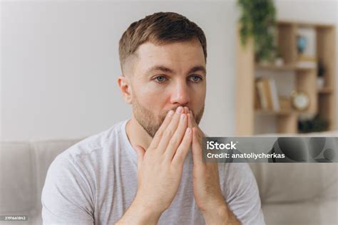 턱수염을 기르고 아픈 슬픈 남자가 집 소파에 앉아 콧물 독감 질병 코로나 바이러스 전염병 코로나 전염병 재채기를 앓고 있습니다 30 34세에 대한 스톡 사진 및 기타 이미지