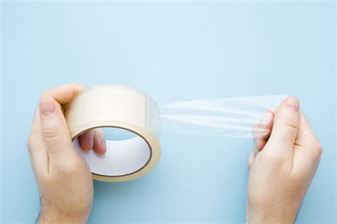 남자 손 스트레칭 투명 스카치 밝은 파스텔 파란색 배경입니다 근접 촬영 평면도 접착 테이프에 대한 스톡 사진 및 기타 이미지 접착 테이프 투명한 말기 Istock