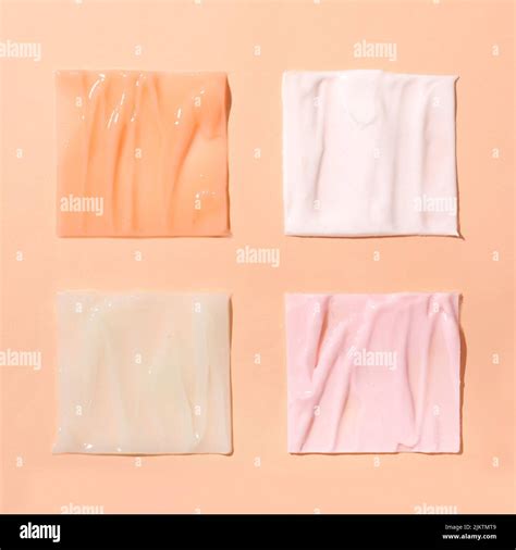 A Top View Of Four Pastel Colored Square Skincare Texture Swatches On A Pink Background Stock