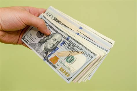 Handing 100 Dollar Bill To Viewer Isolated On Green Background Stock
