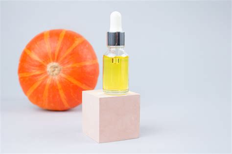 호박 씨앗으로 만든 천연 유기농 화장품 오일 스킨 케어 용 화장품 오일 추출물 또는 호박이있는 회색 배경의 머리카락을 곁들인 점적기 병 미용 치료 선택적 초점 한방 의학