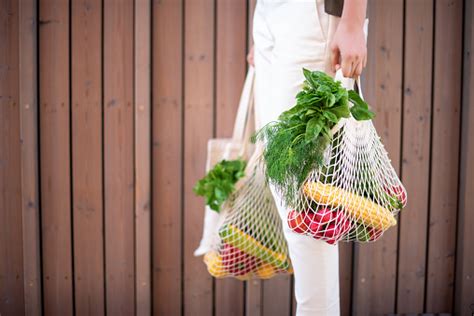 비닐 봉지 나무 배경없이 야채와 메쉬 쇼핑 백과 면 구매자를 들고 소녀 제로 폐기물 플라스틱 무료 개념 지속 가능한 라이프