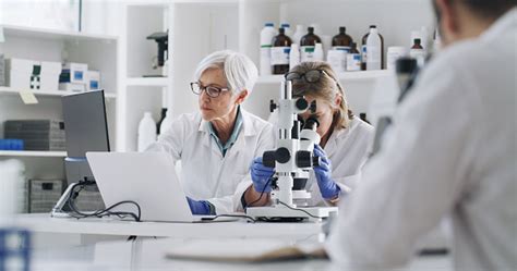 과학 연구 팀워크 및 과학자 과학 실험실에서 혁신 솔루션 및 분석을위한 기술 노트북 및 현미경을 가진 사람들 책상에서 데이터