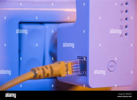 Insert Ethernet Cable Into Wifi Extender Device Which Is In Electrical Socket On The Wall The