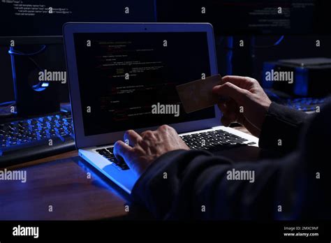 hacker with computers and credit card in dark room closeup cyber
