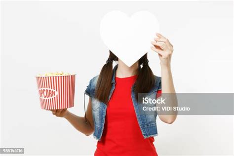 영화 영화를 보고 팝콘의 물통을 들고와 복사 공간 흰색 배경에 고립 된 하얀 마음으로 얼굴을 덮고 캐주얼 옷에 젊은 갈색 머리